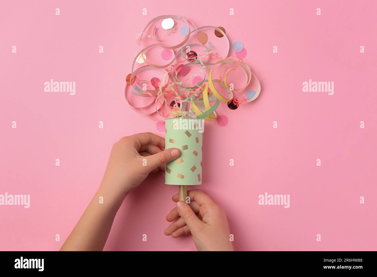 Woman holding party popper with serpentine and confetti on pink ...