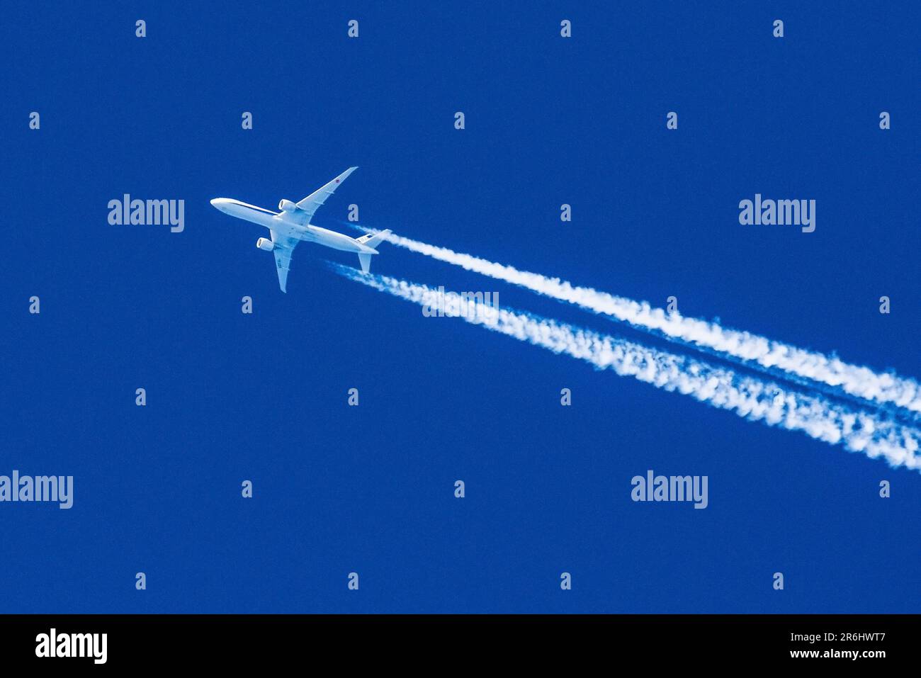 Sharp telephoto close-up of jet plane aircraft with contrails cruising ...