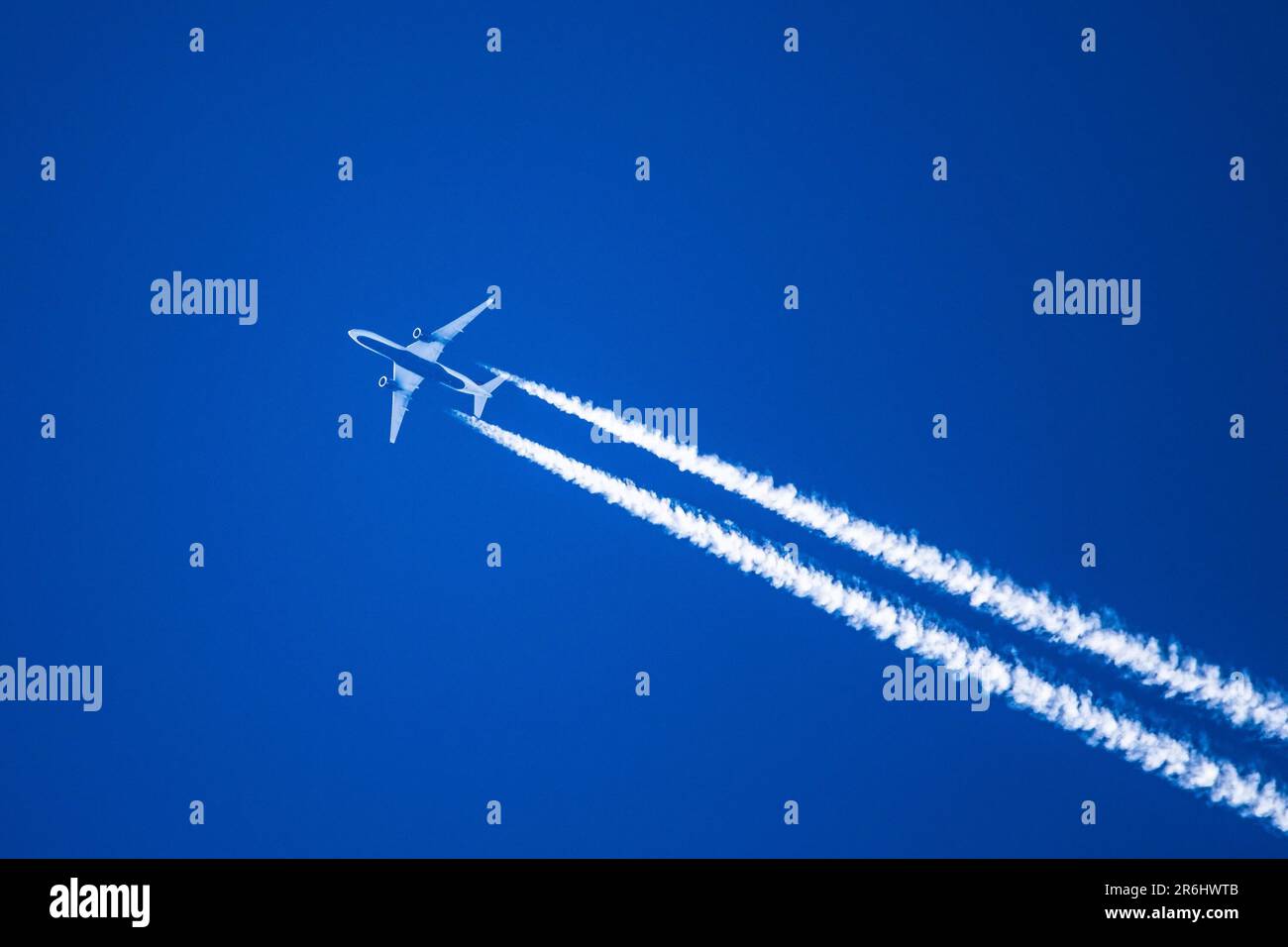 Sharp telephoto close-up of jet plane aircraft with contrails cruising ...