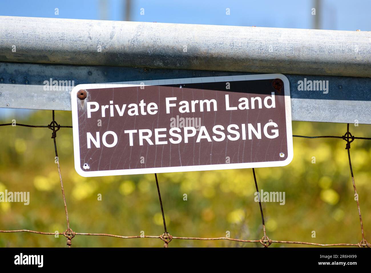 Private Farm Land No Trespassing sign posted on a wire fence. Close up ...