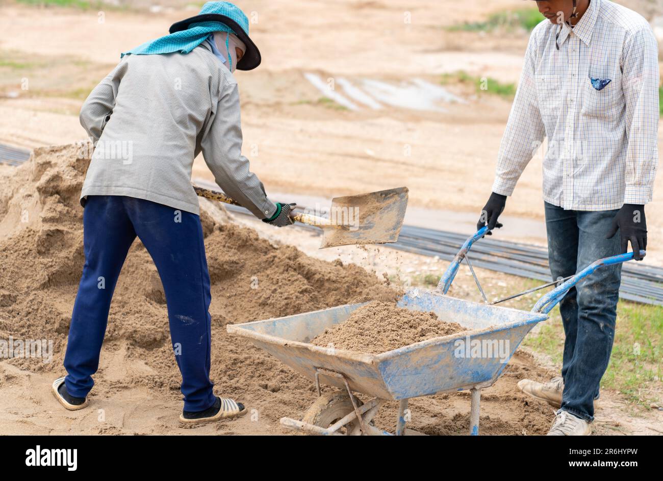 Worker pours sand from a large pile of sand onto a construction ...