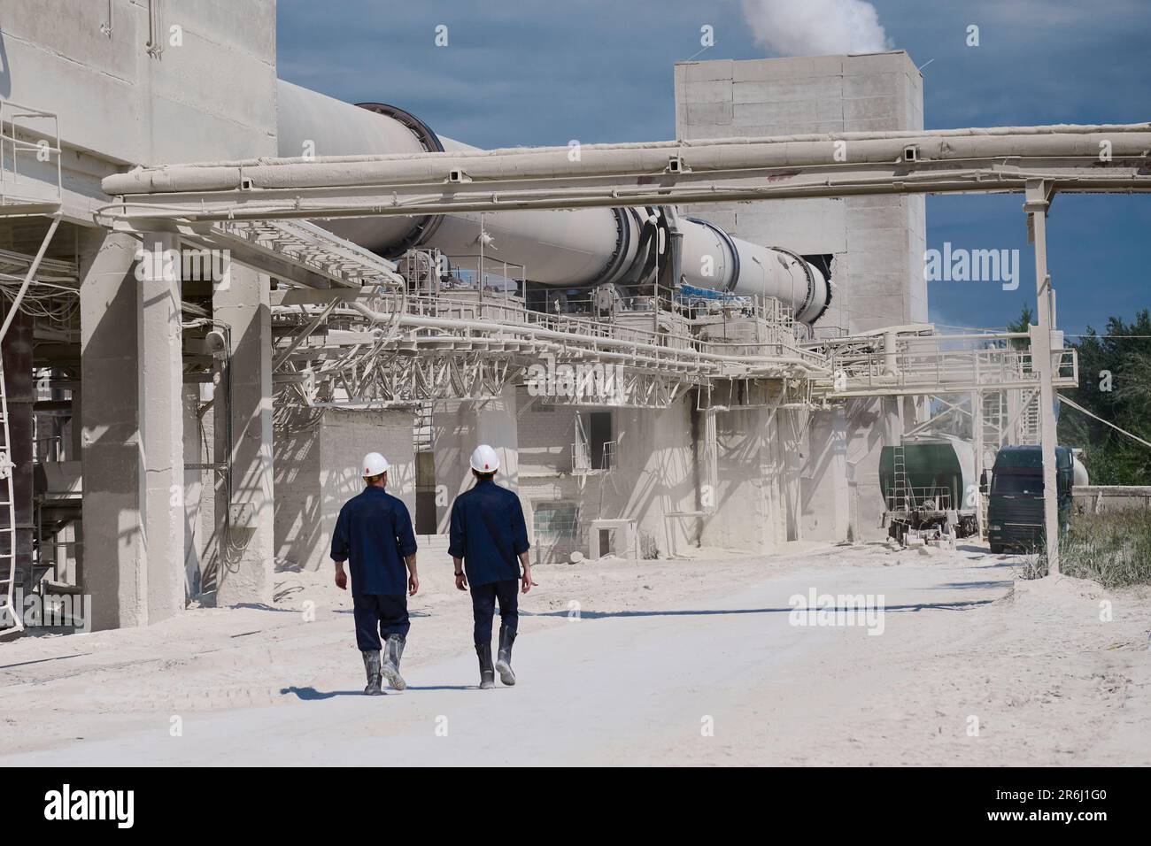 Workers in uniforms walk across yard of huge lime plant Stock Photo - Alamy