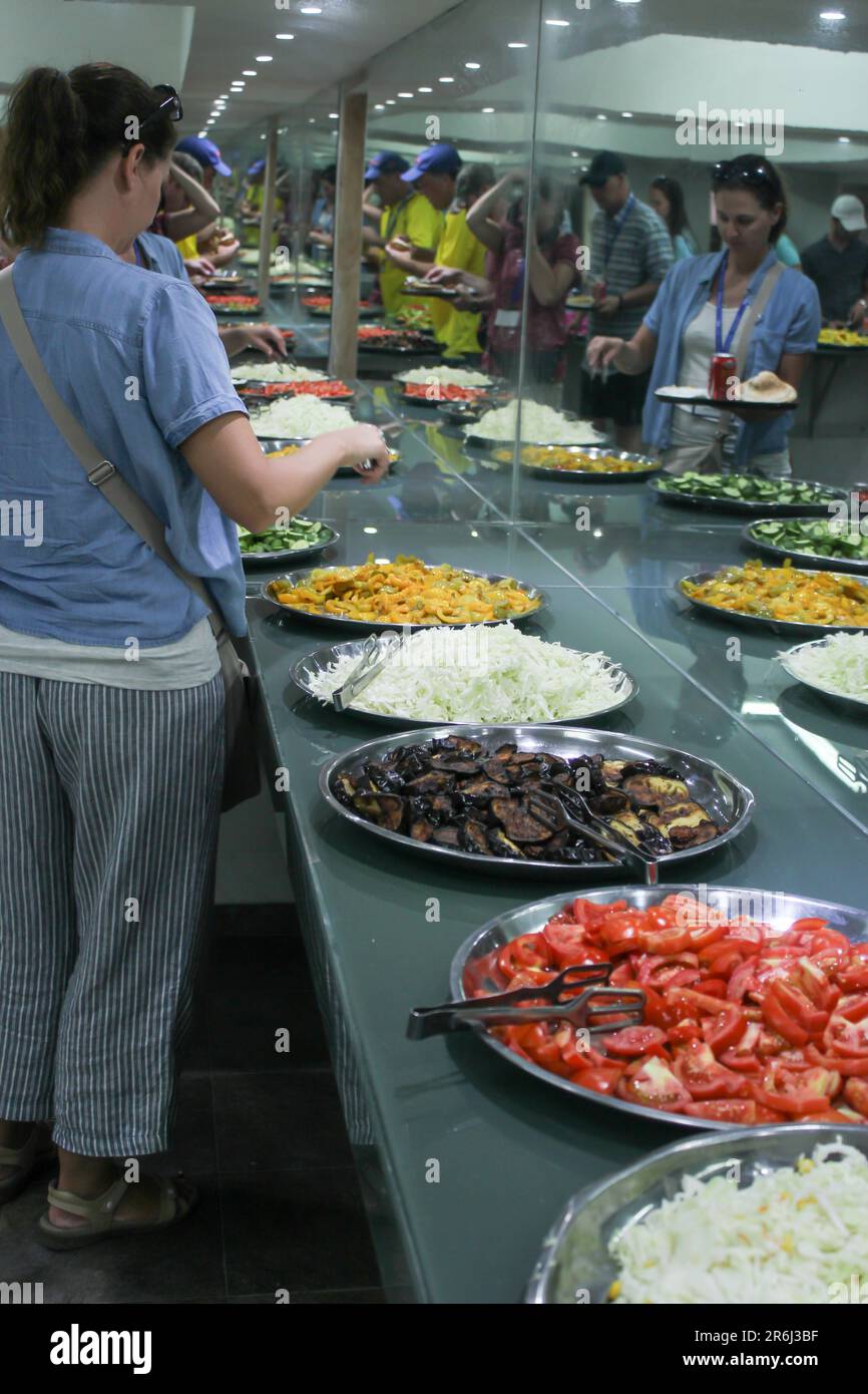 A young woman chooses her meal from a selection of fresh food displayed ...