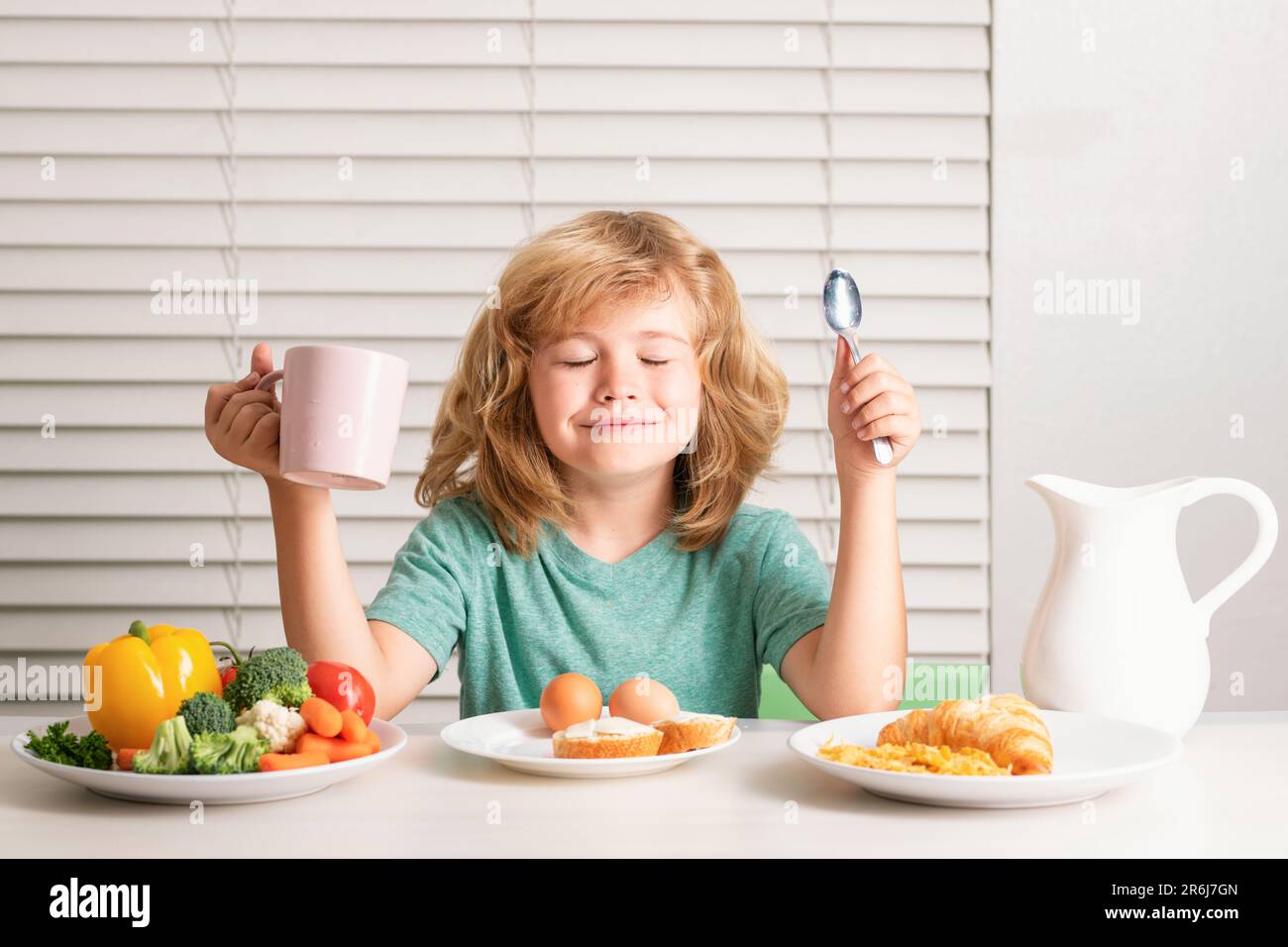 Kid boy eating healthy food vegetables. Breakfast with milk, fruits and ...