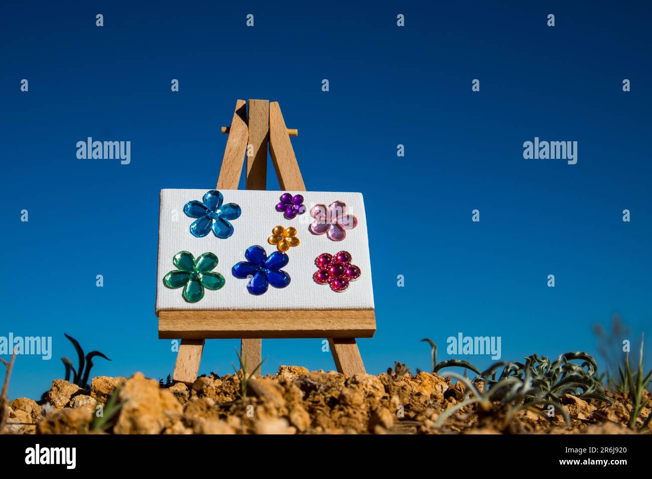 Wooden miniature easel with shiny artificial multicolored blooming ...