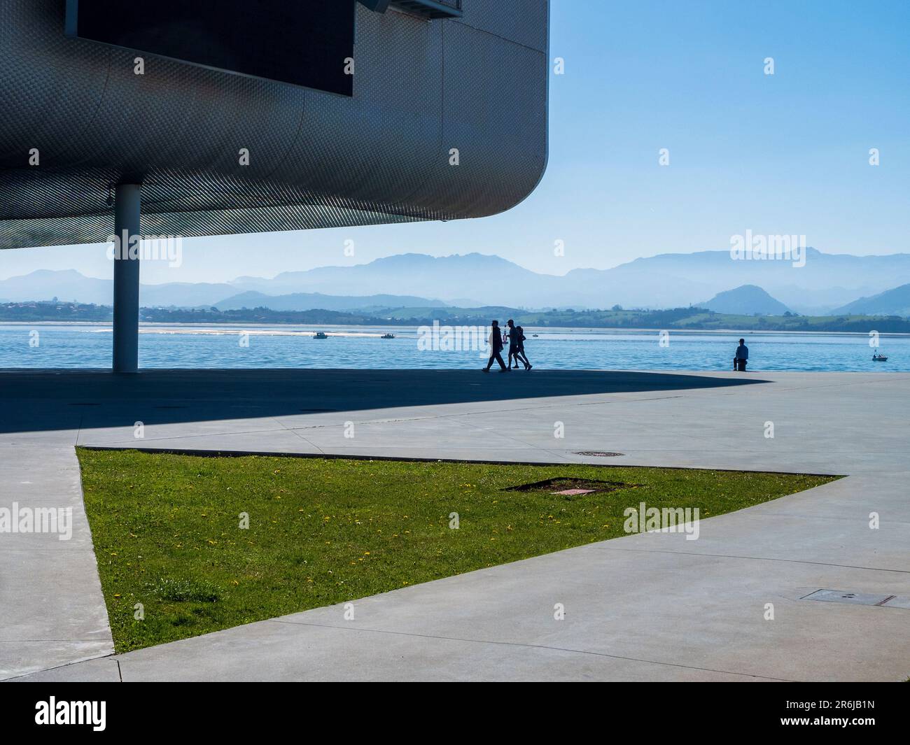 Silhouettes of people walking along a quay in the port of Santander ...