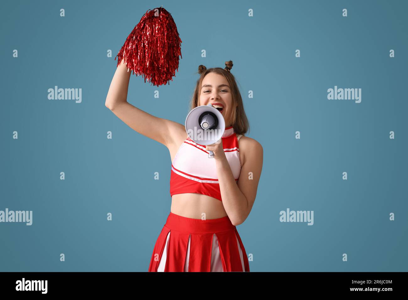 Beautiful cheerleader shouting into megaphone on blue background Stock ...
