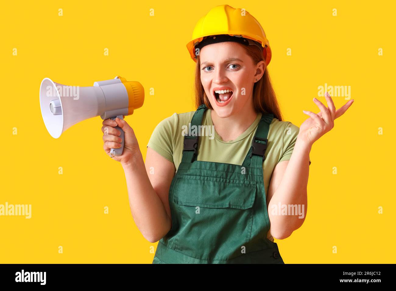 Female builder shouting into megaphone on yellow background Stock Photo ...