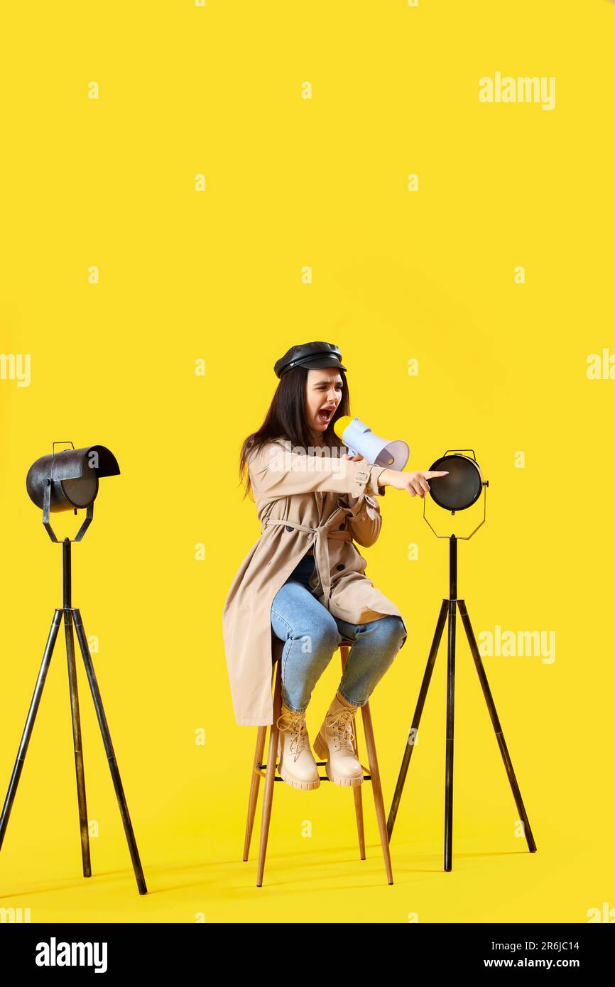 Female film director shouting into megaphone on yellow background Stock ...