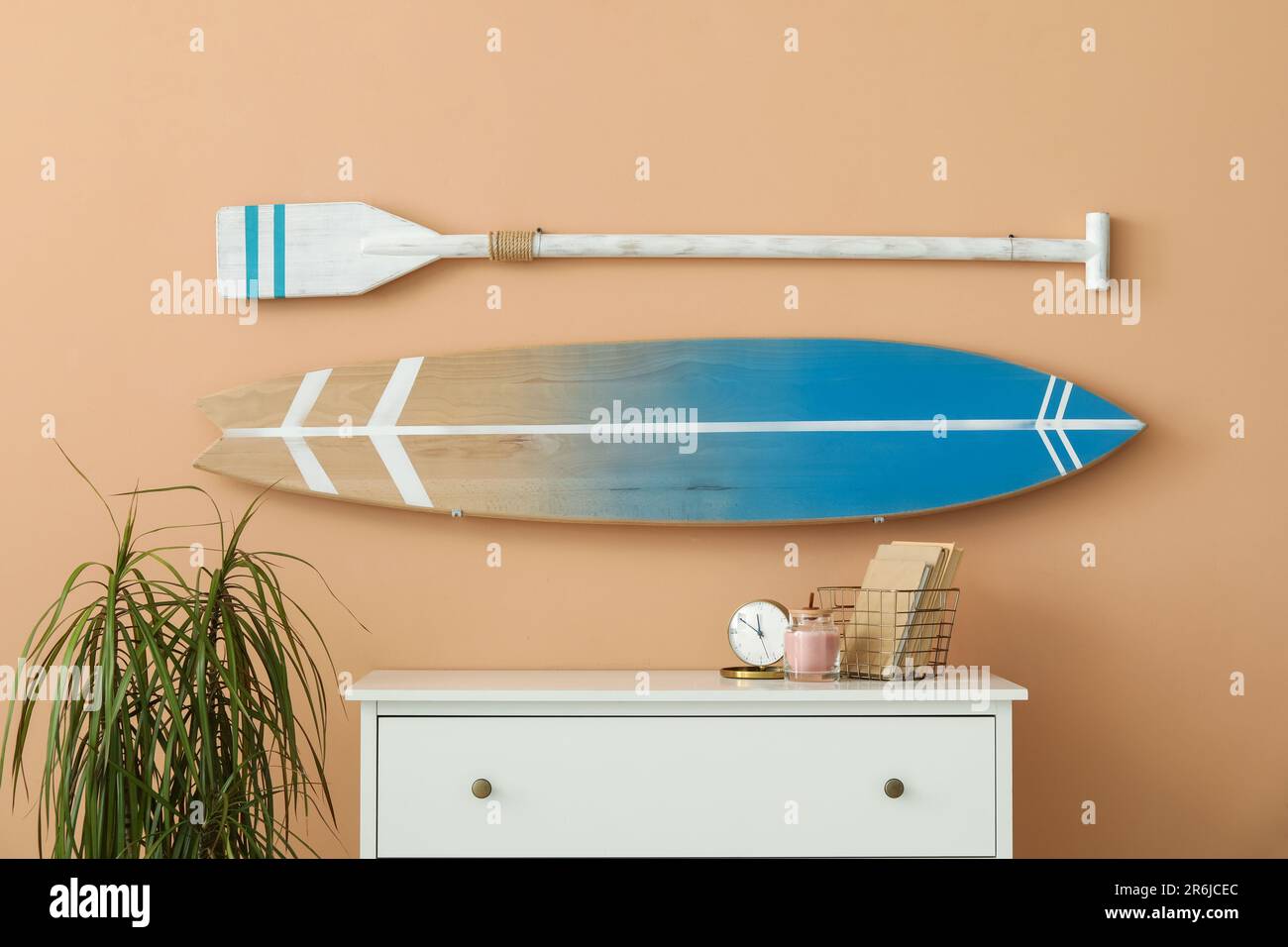 Surfboard and paddle hanging on beige wall in room Stock Photo - Alamy