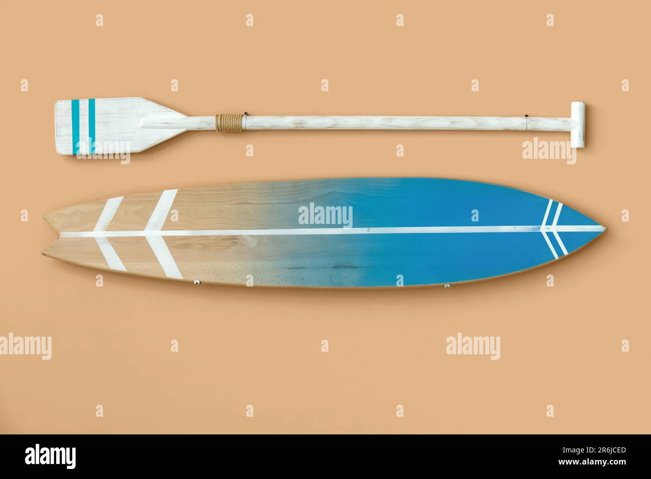 Wooden surfboard and paddle hanging on beige wall Stock Photo - Alamy