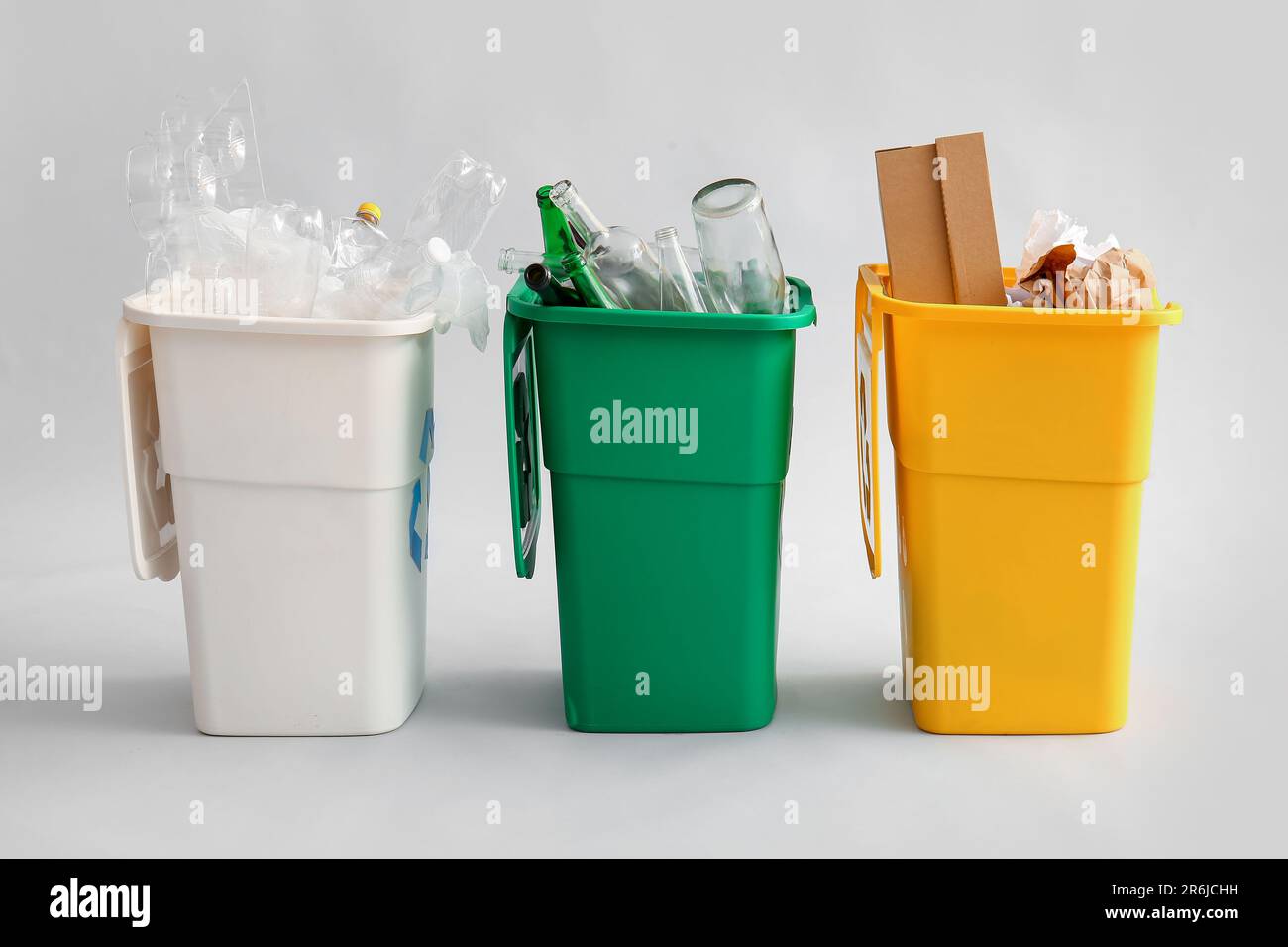 Containers with different types of garbage on light background ...