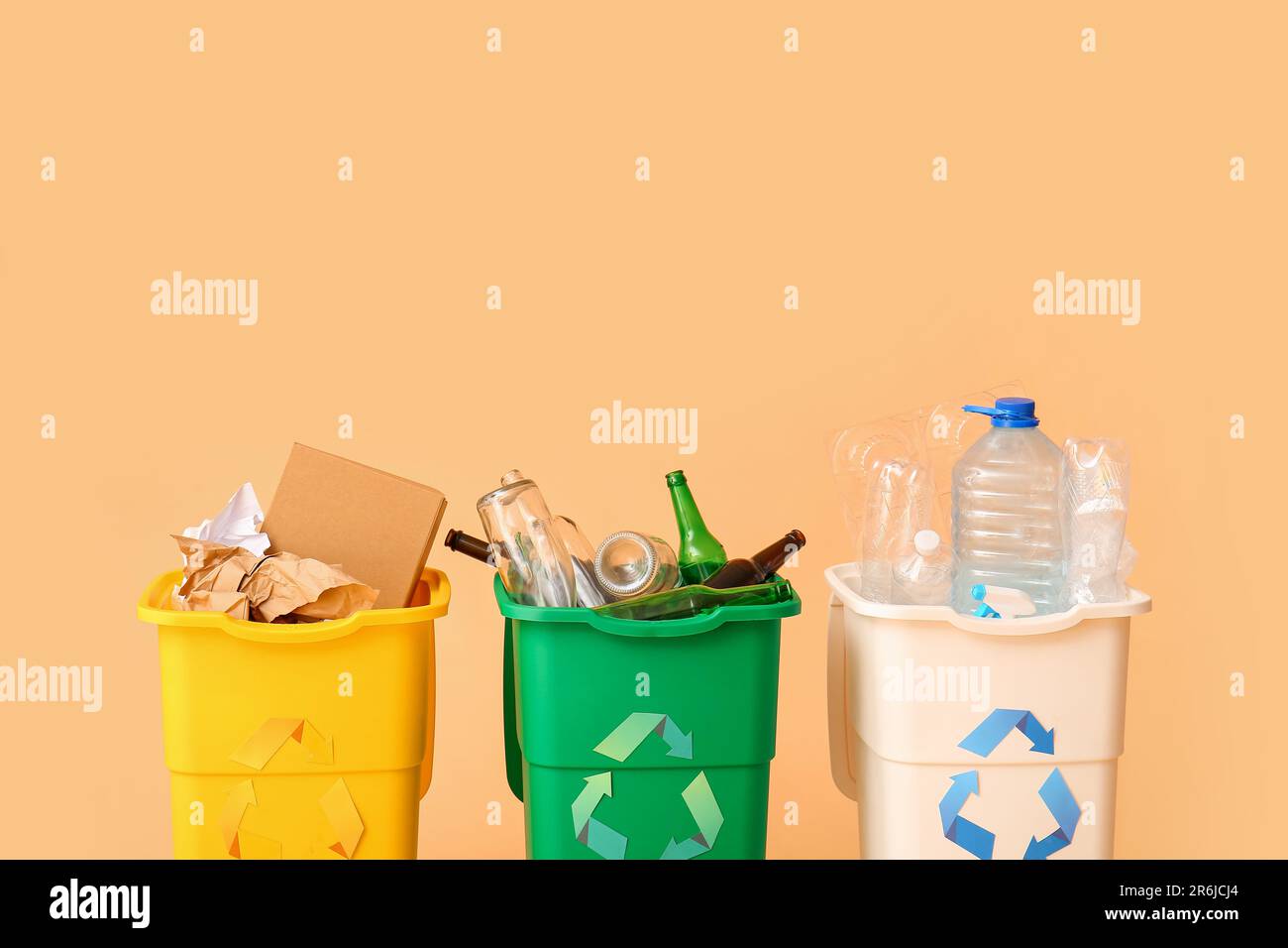 Containers with different types of garbage on beige background ...