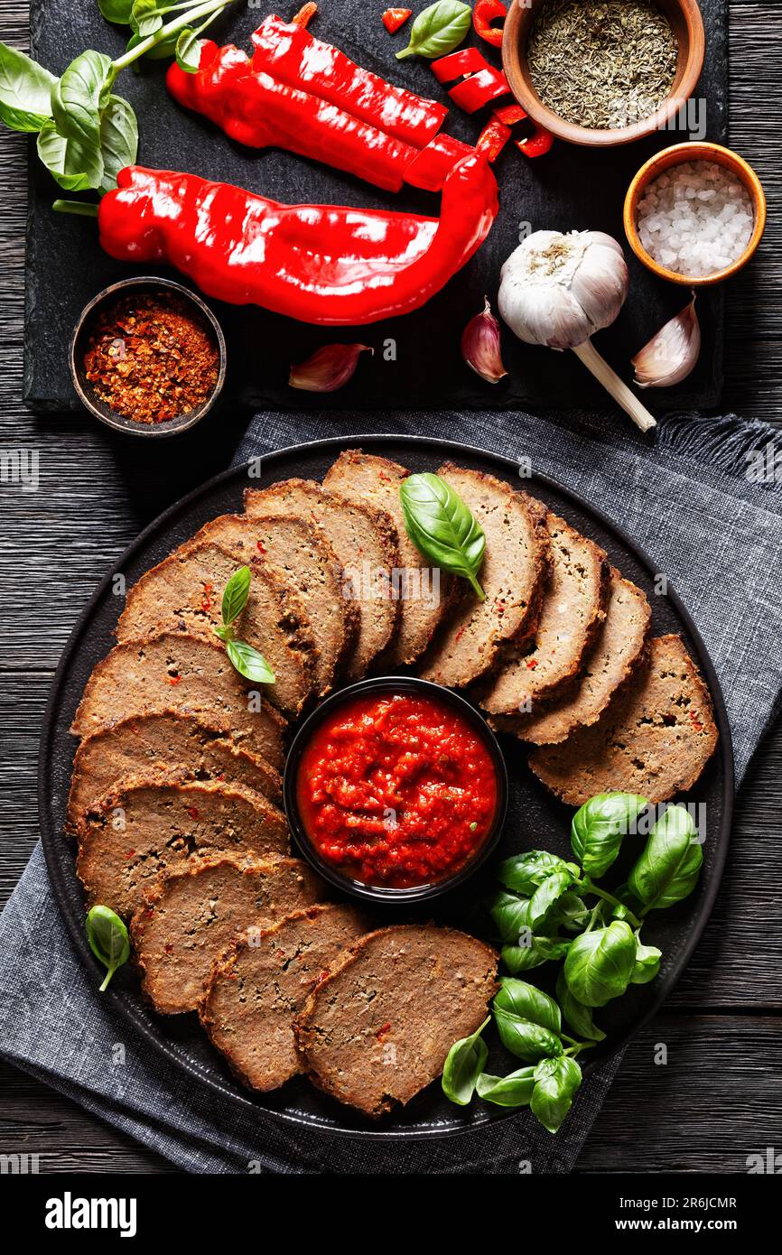italian style meatloaf cut in slices on black platter on dark wood ...
