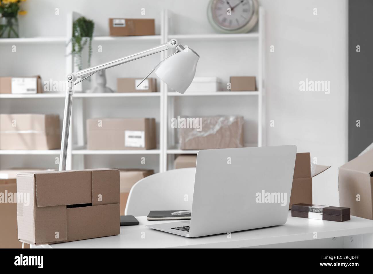 Workplace with laptop and parcels in office Stock Photo - Alamy