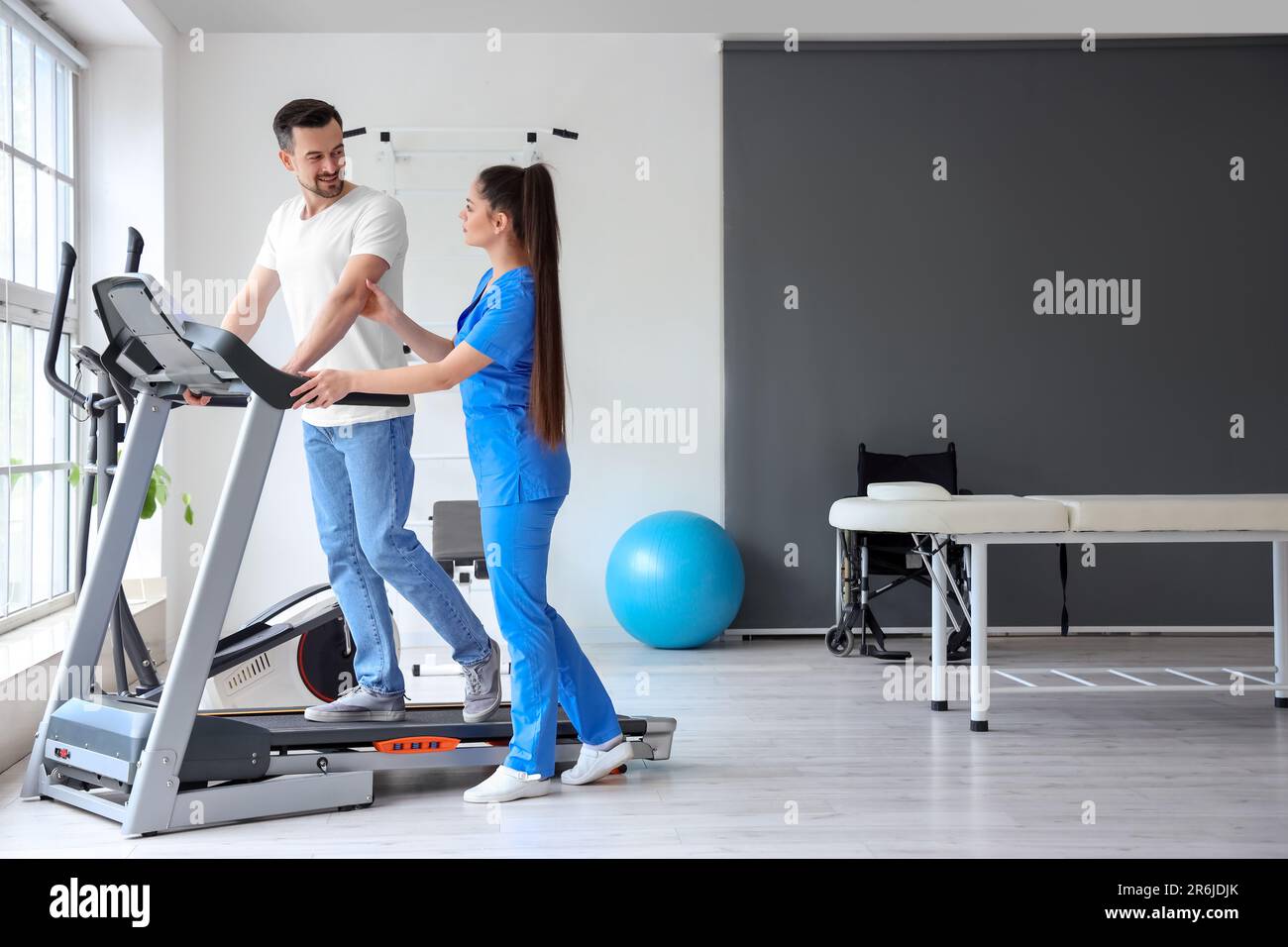 Female physiotherapist working with young man on treadmill in ...