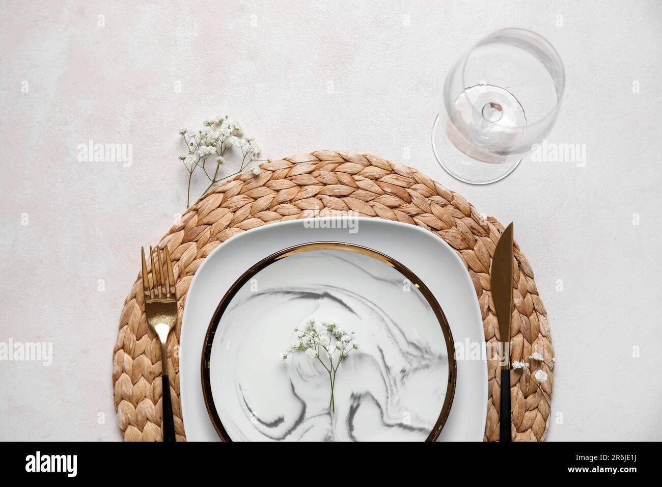 Wicker mat with plates, gold cutlery and glass on grunge white ...