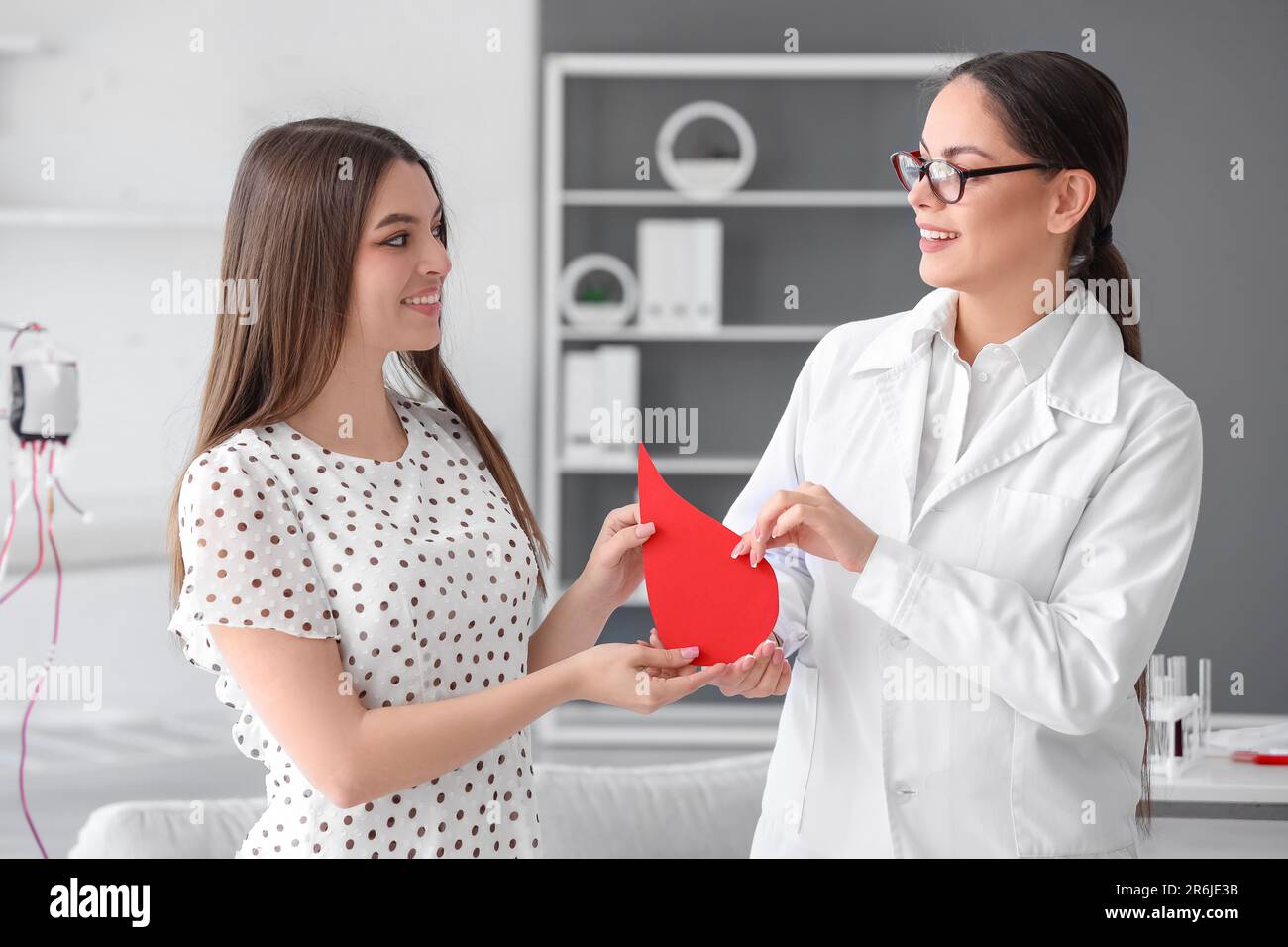 Female doctor and young donor with paper blood drop in clinic Stock ...
