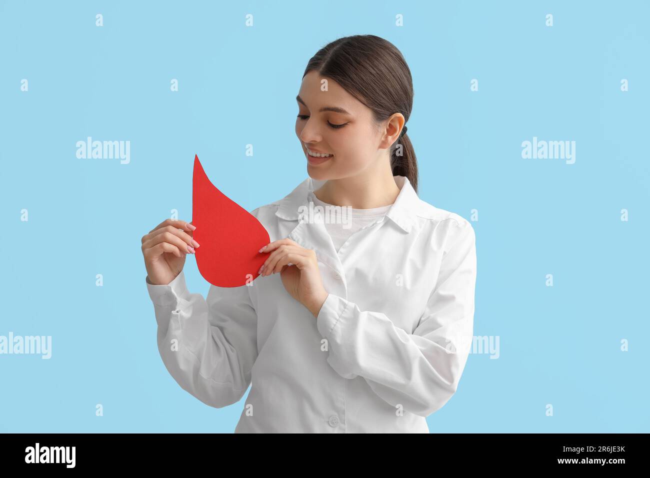 Female doctor with paper blood drop on blue background Stock Photo - Alamy