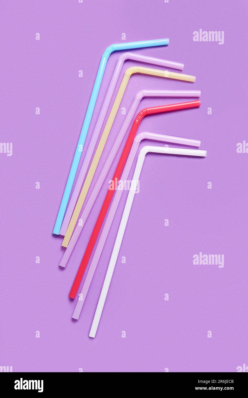 Different plastic straws on purple background Stock Photo - Alamy