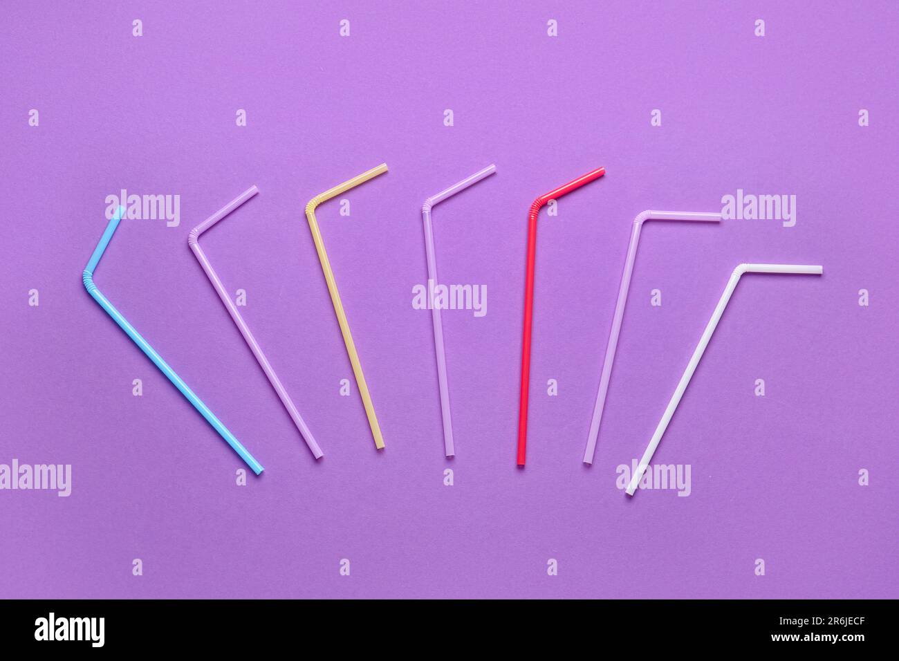 Different plastic straws on purple background Stock Photo - Alamy