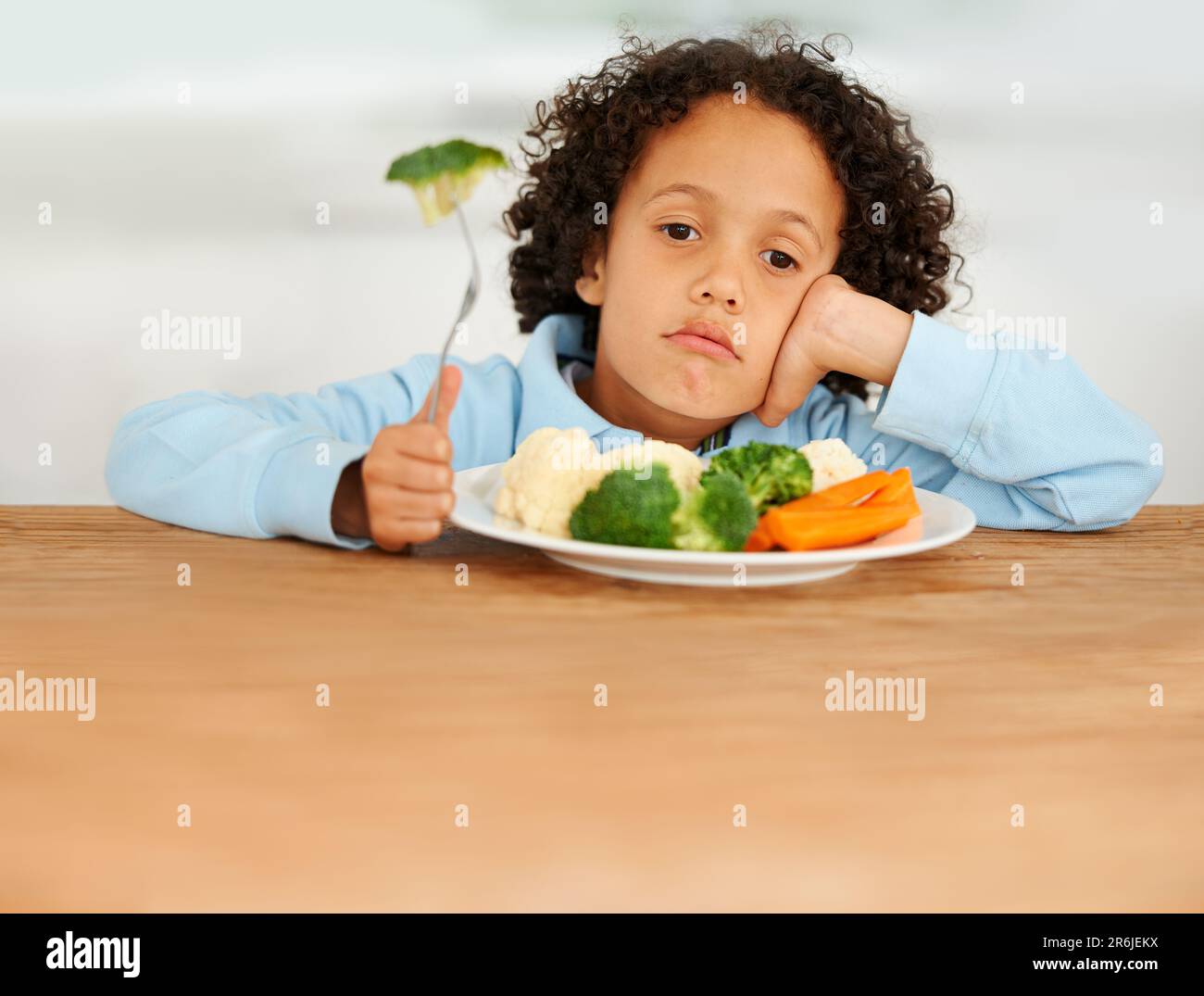 Bored, upset and child eating vegetables for a healthy, growth and ...
