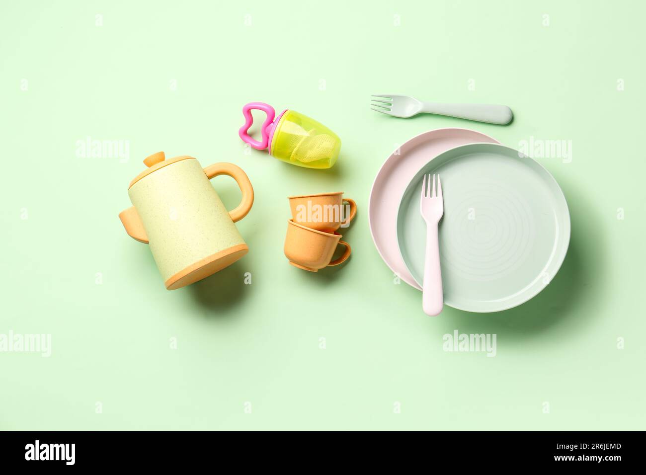 Different eating utensils for baby on pale green background Stock Photo ...