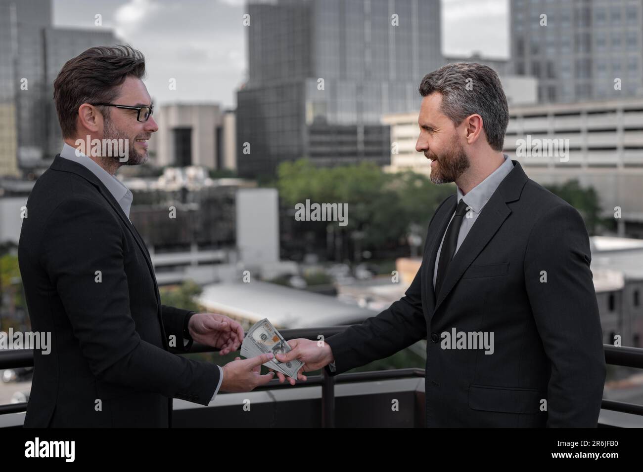 Investor in suits giving dollar banknotes. Businessman giving money ...