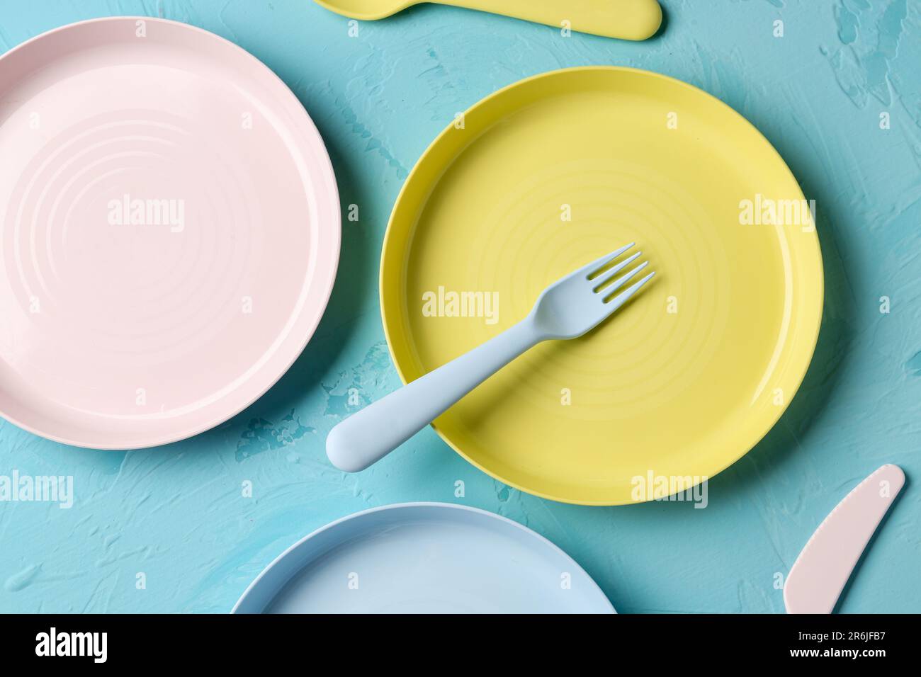 Colorful plates with eating utensils for baby on grunge blue background ...