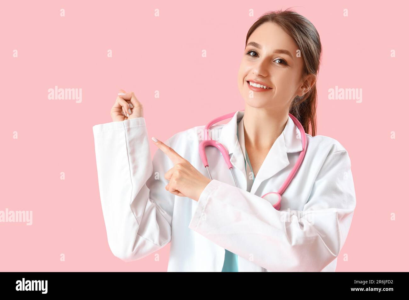 Female medical intern pointing at something on pink background Stock ...