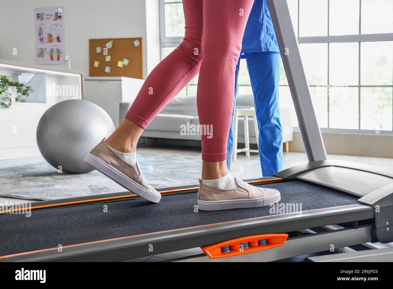 Female physiotherapist working with mature woman on treadmill in ...