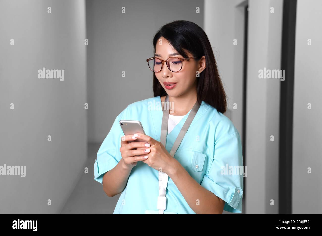 Female Asian medical intern using mobile phone in clinic Stock Photo ...