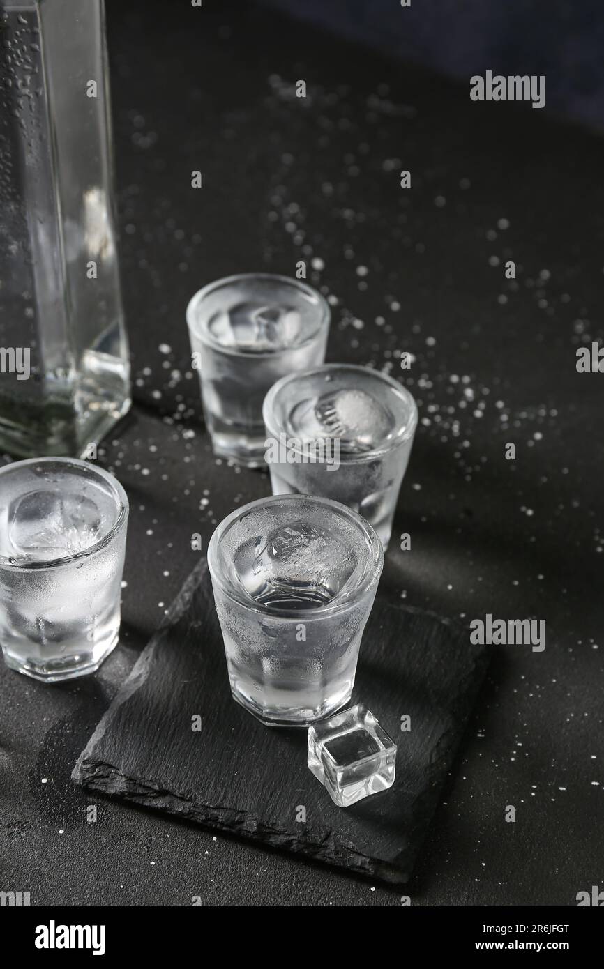 Shots of vodka with ice cubes on black background Stock Photo - Alamy