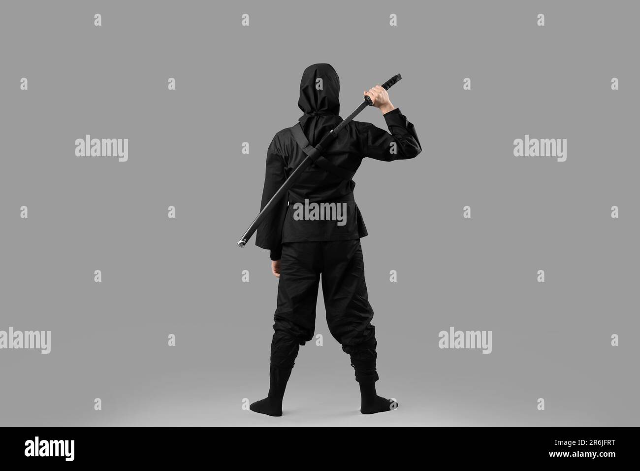 Male ninja with sword on grey background, back view Stock Photo - Alamy