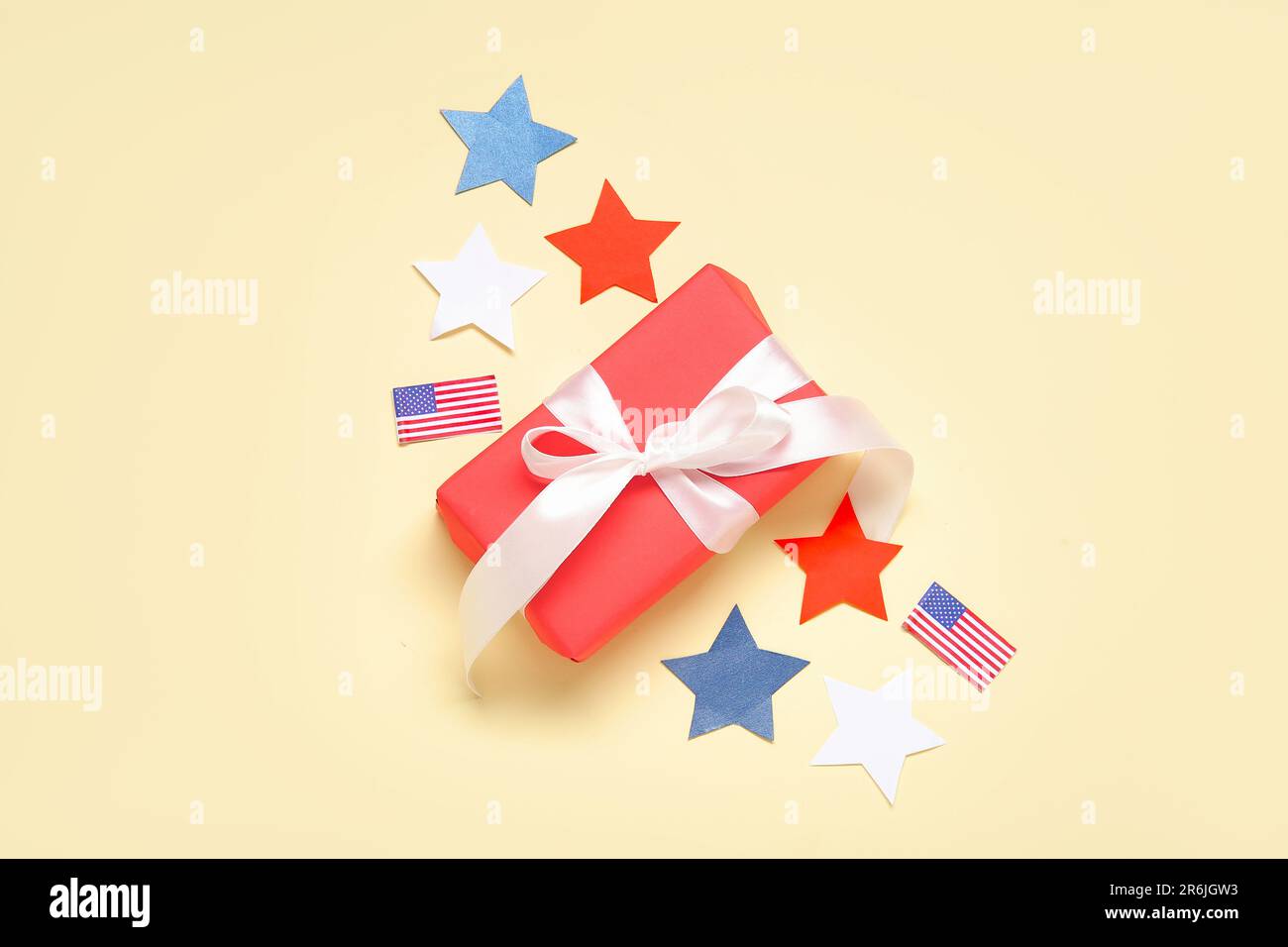 Gift box with USA flags and stars on pale yellow background. American ...
