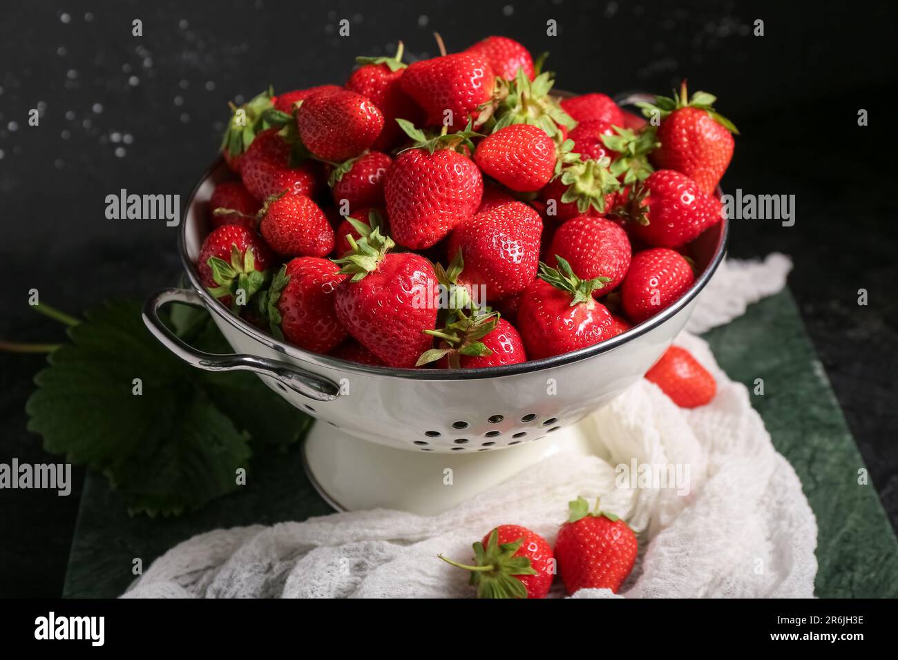 Colander with fresh strawberries on black background Stock Photo - Alamy