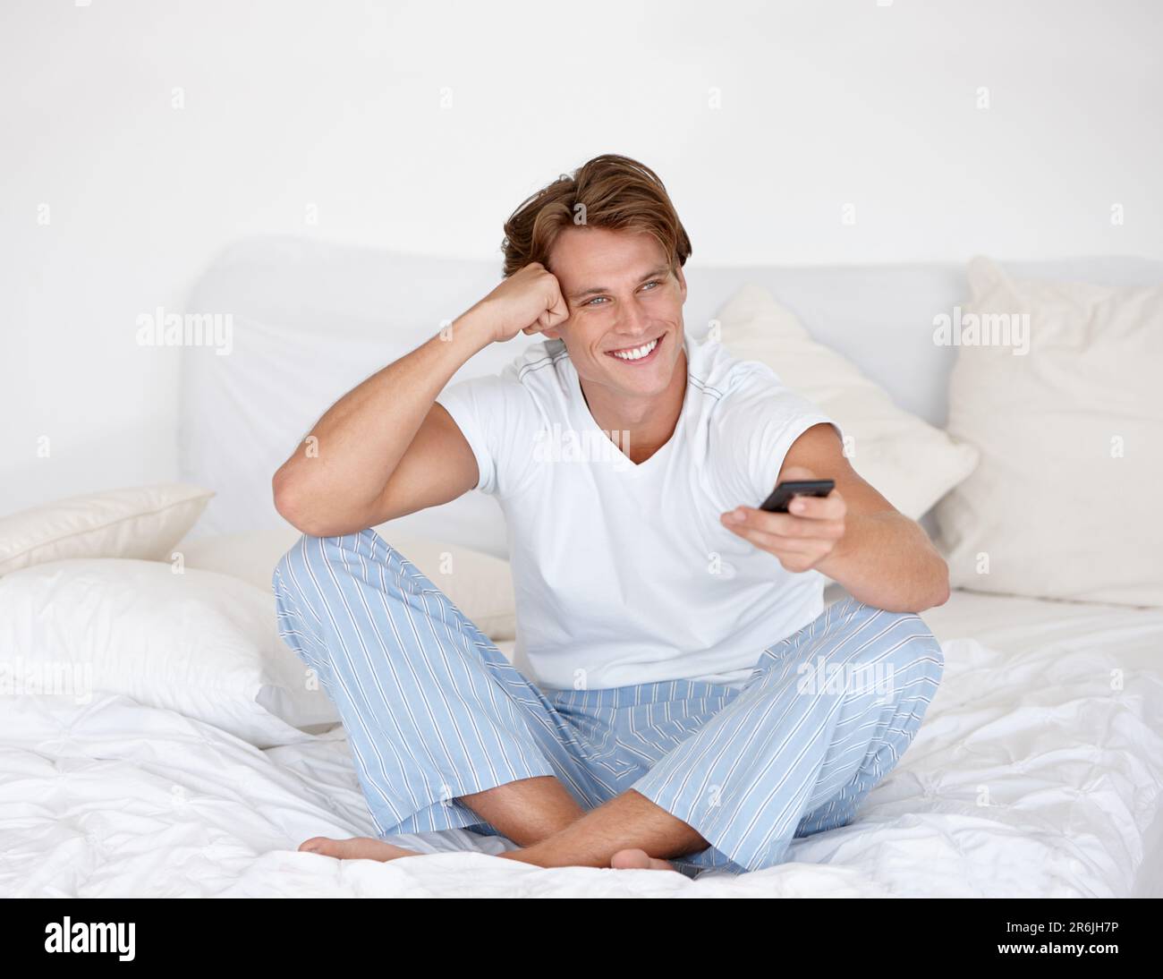 Man, smile and watching tv on a bedroom bed feeling relax with remote ...