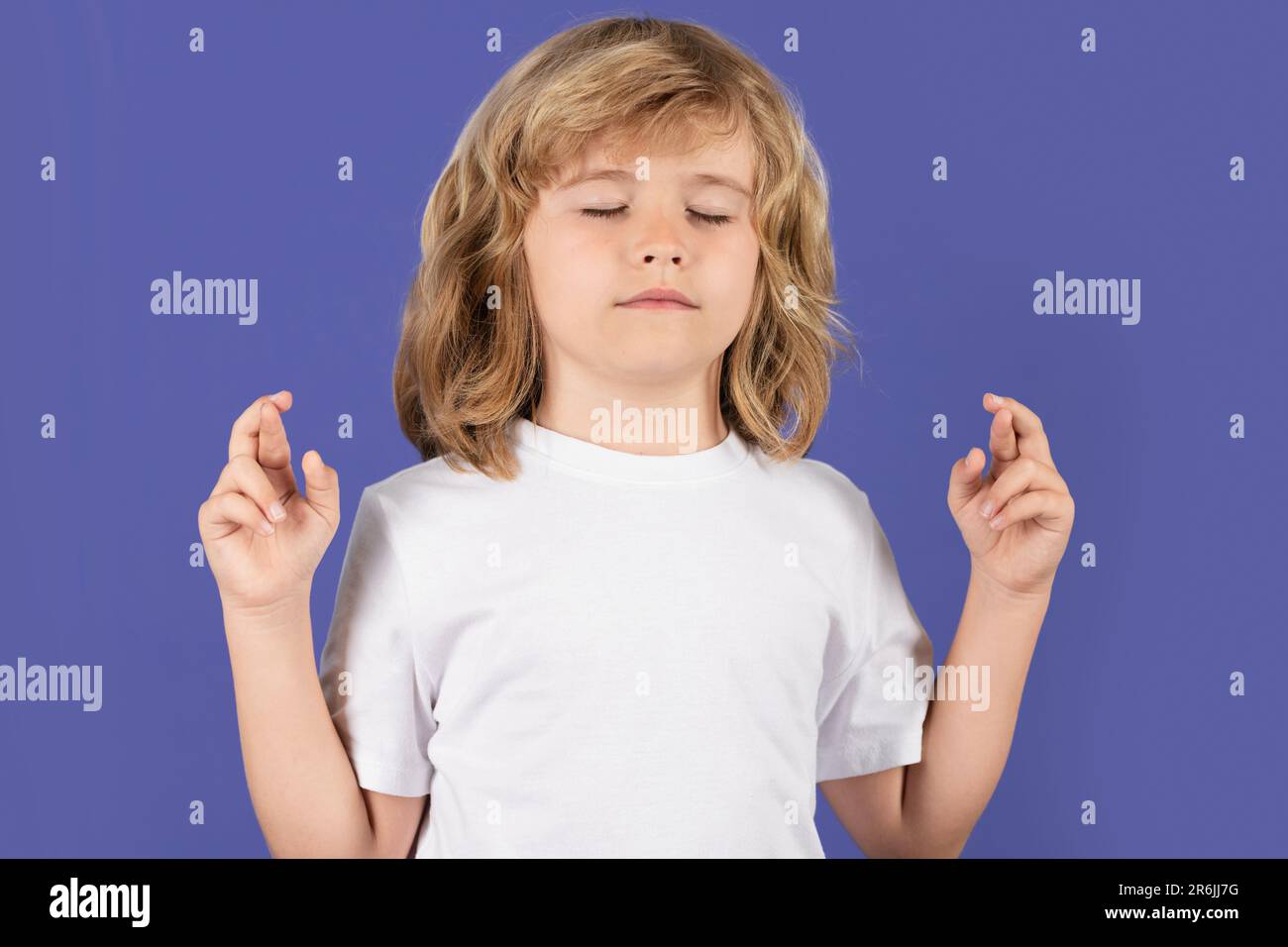 Kid boy crossed fingers, isolated studio background. Child closed eyes ...