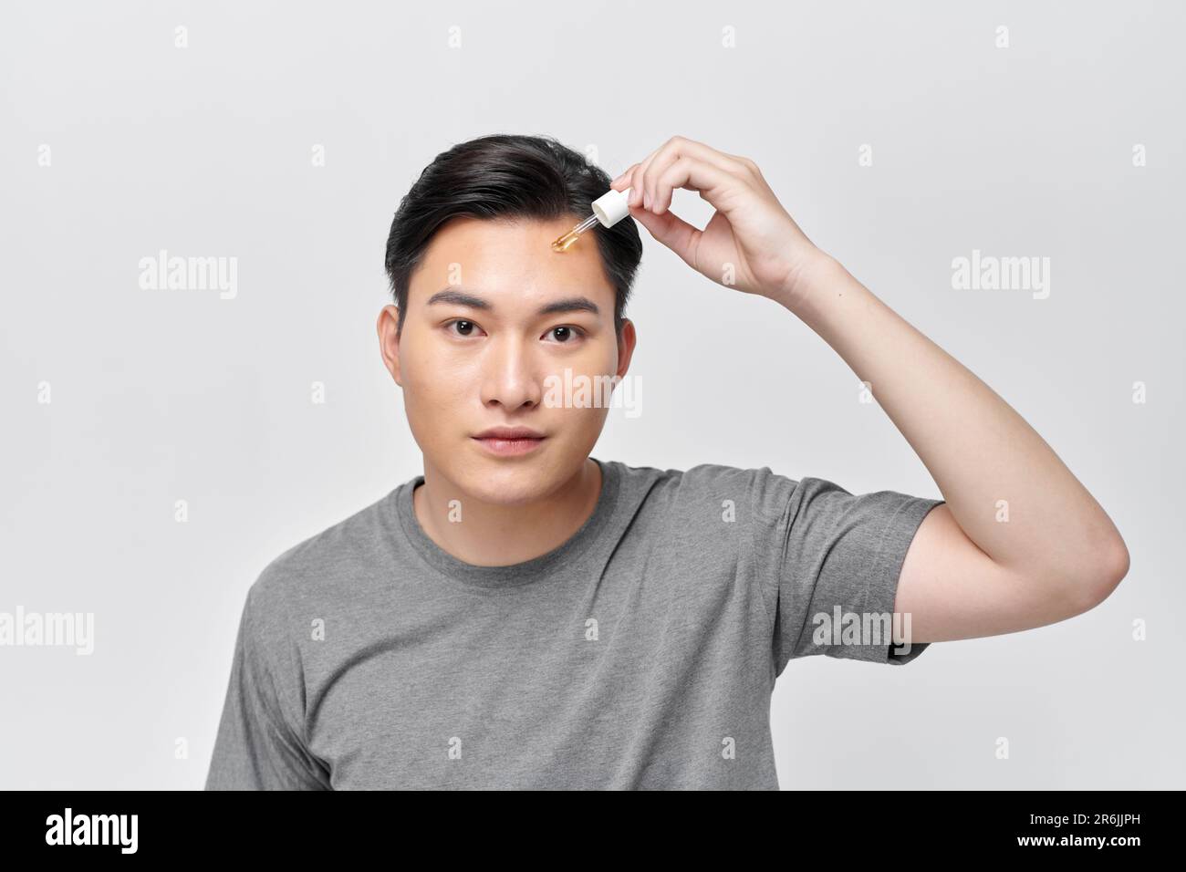 portrait of handsome guy applying serum beauty product on his face ...