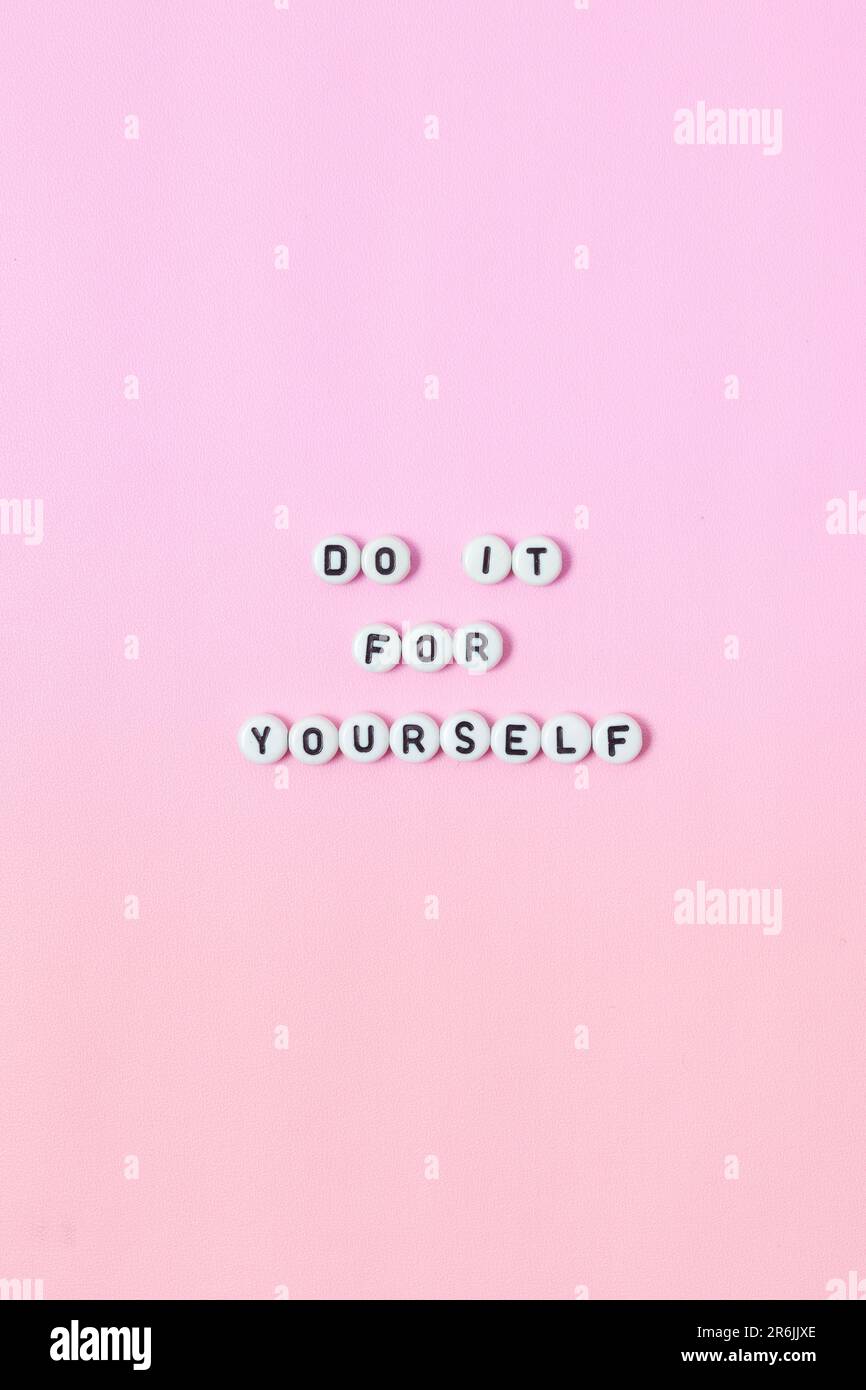 Top view of "do it for yourself" quotes made out of beads on pink ...