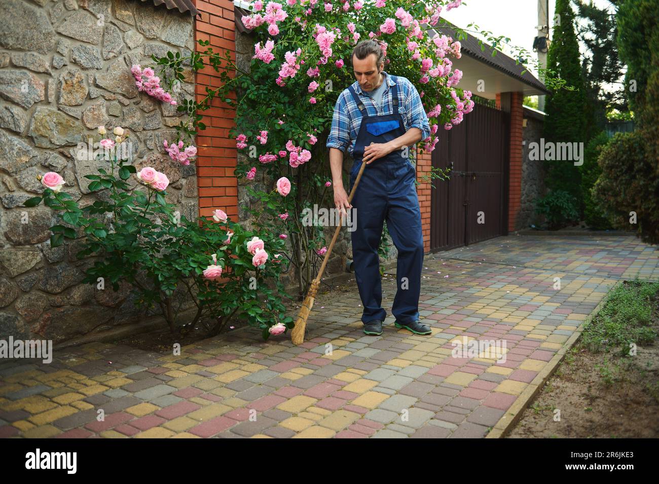 Full length portrait of a male gardener in blue gardening uniform ...