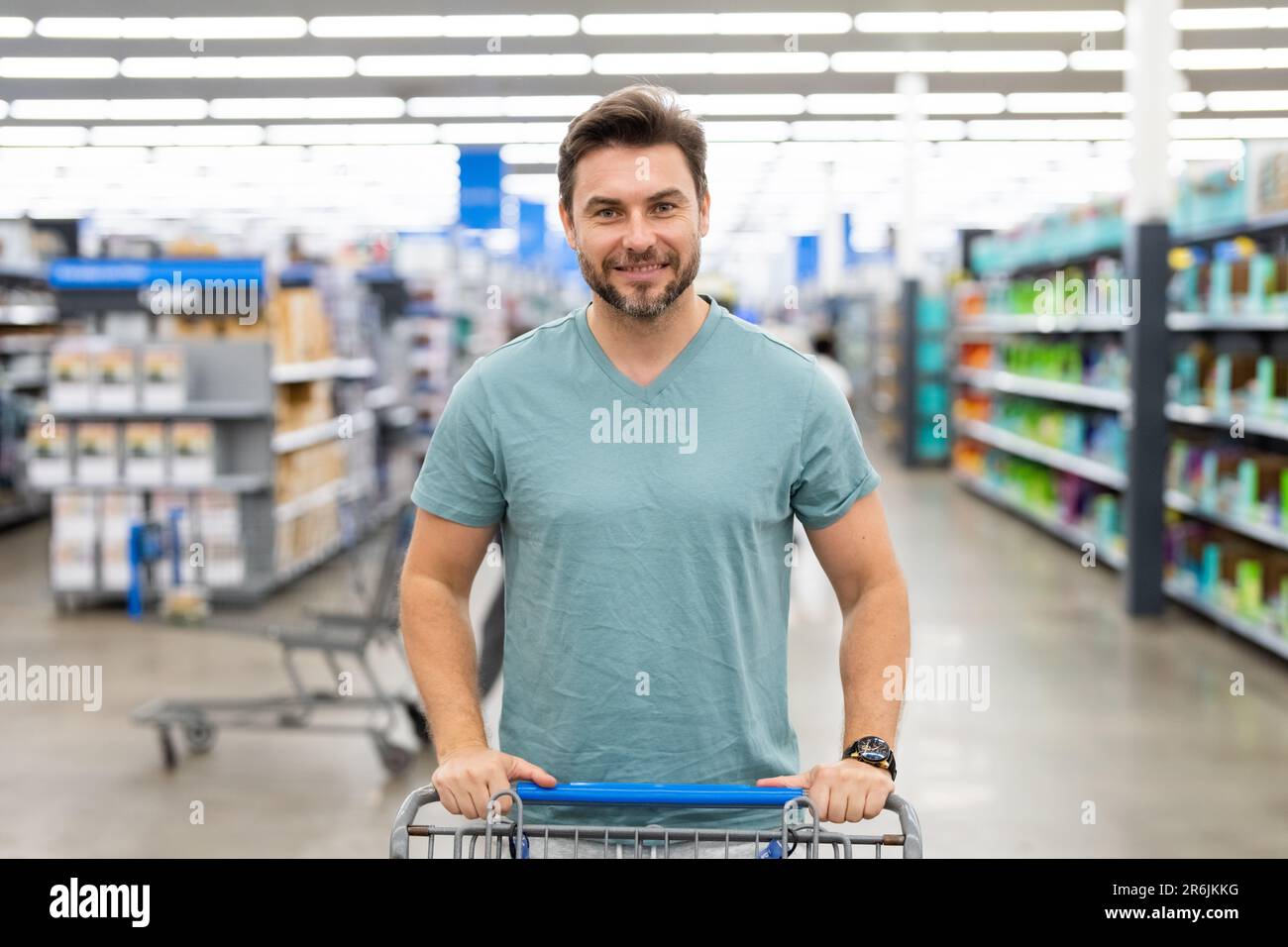 Handsome man with shopping basket with shopping trolley at grocery. Man ...