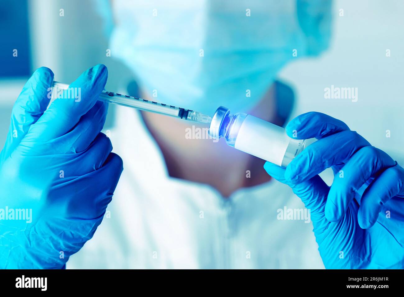 Laboratory worker filling syringe with medication from glass vial in ...