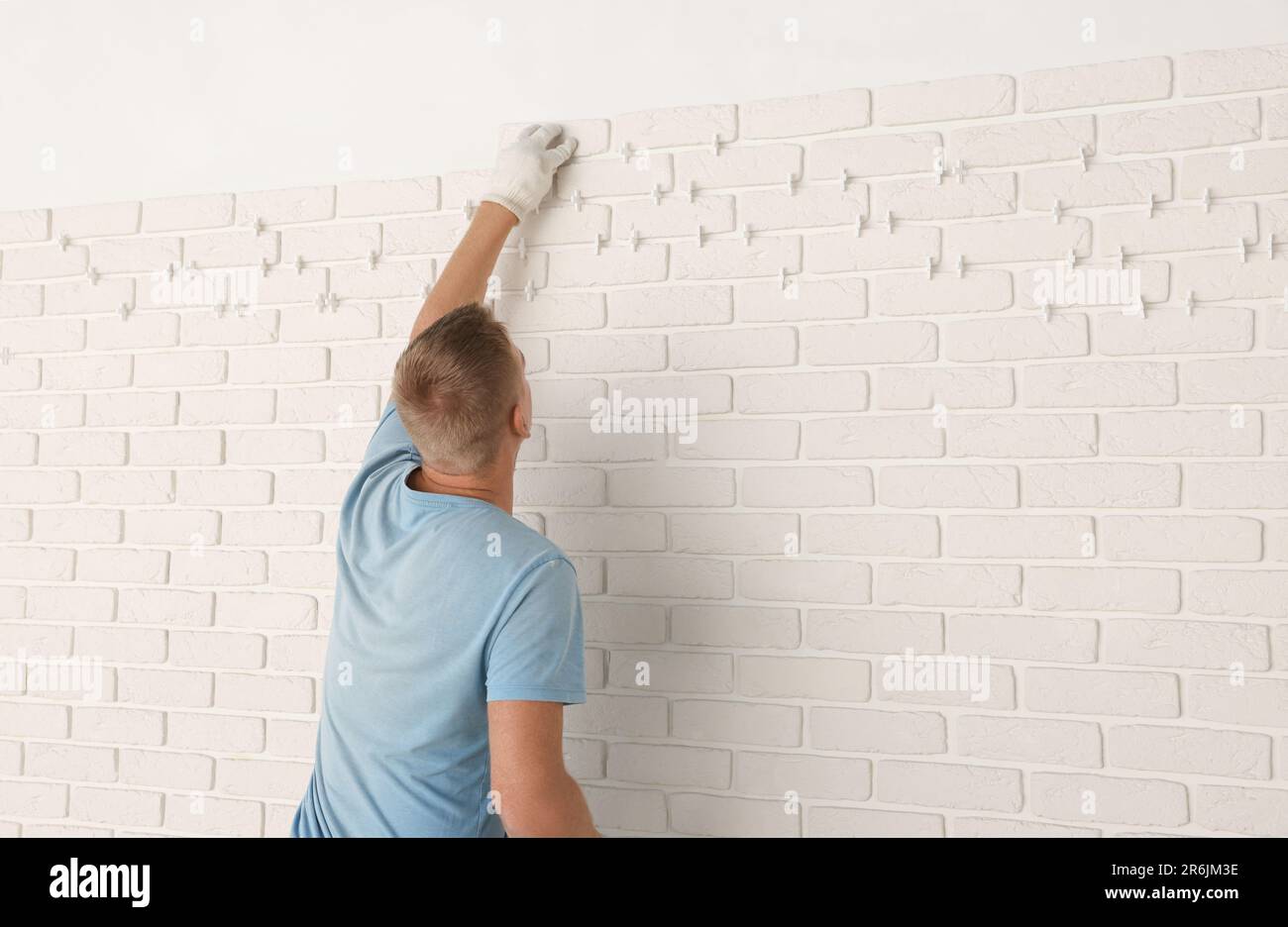 Professional builder installing new white decorative bricks on wall ...