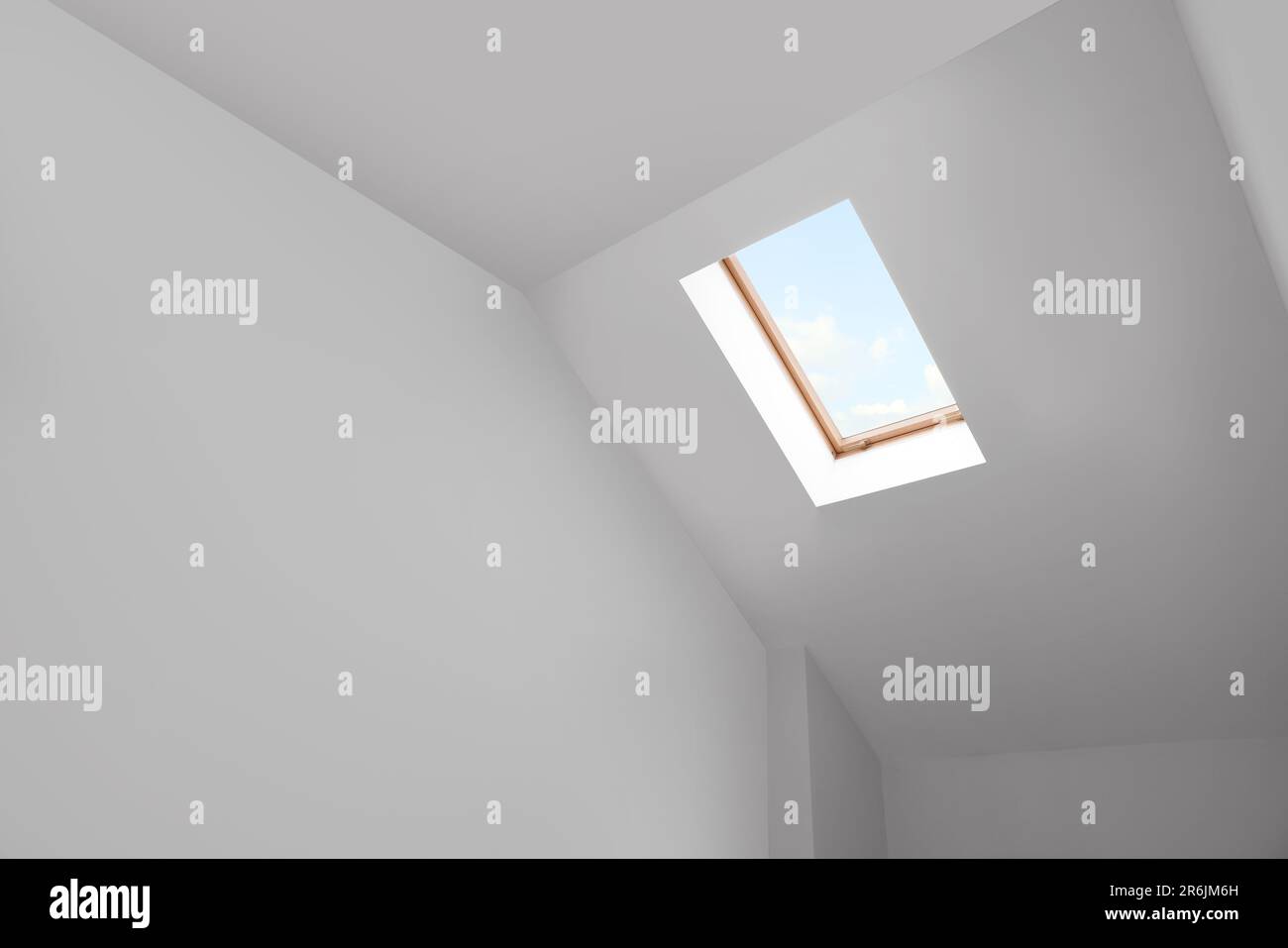 Skylight roof window and lamps on slanted ceiling in attic room, low ...