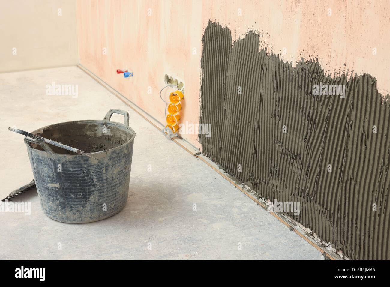 Bucket near white wall with adhesive mix for tile installation indoors ...