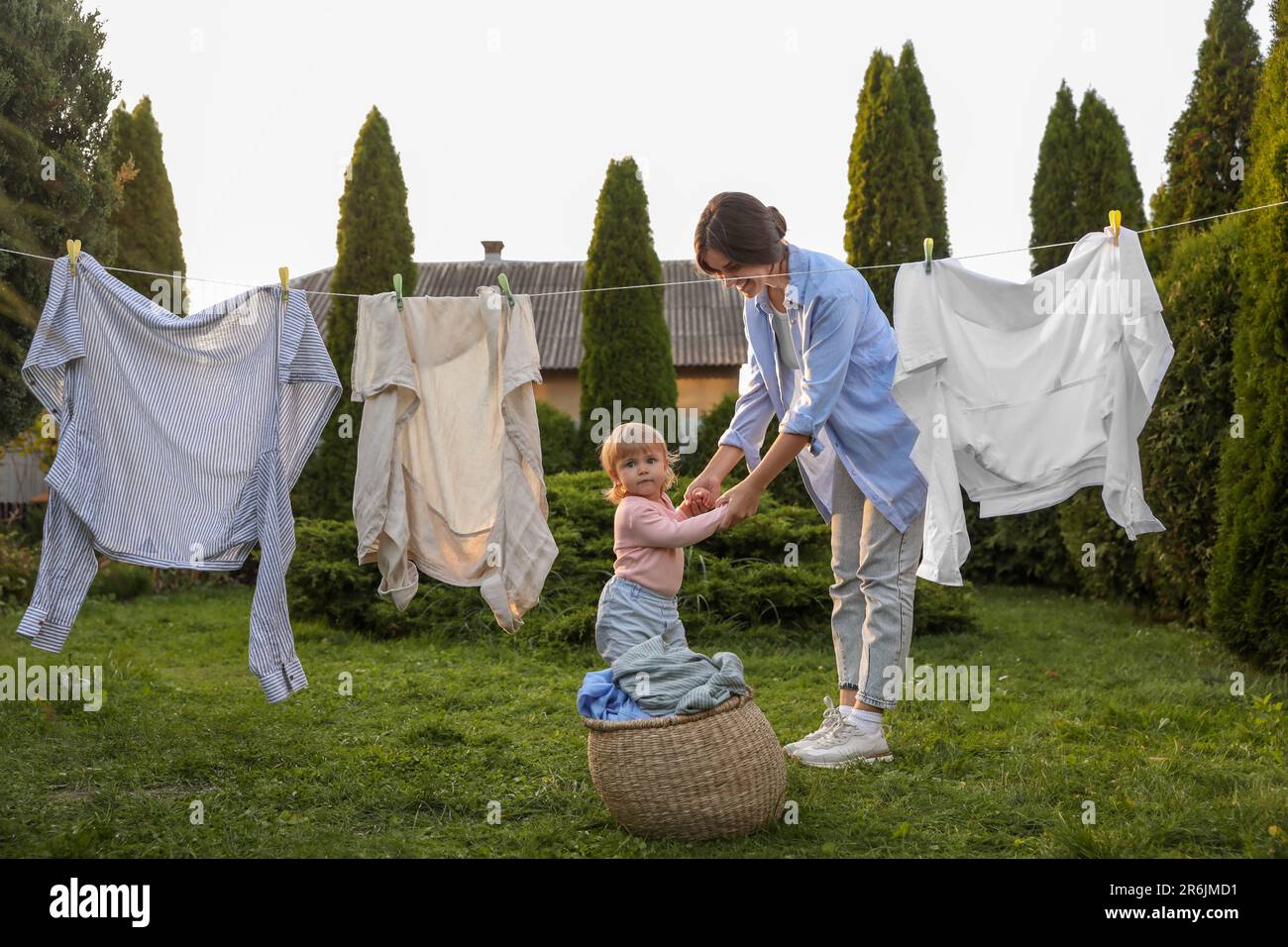 Mother and daughter near washing line with drying clothes in backyard ...
