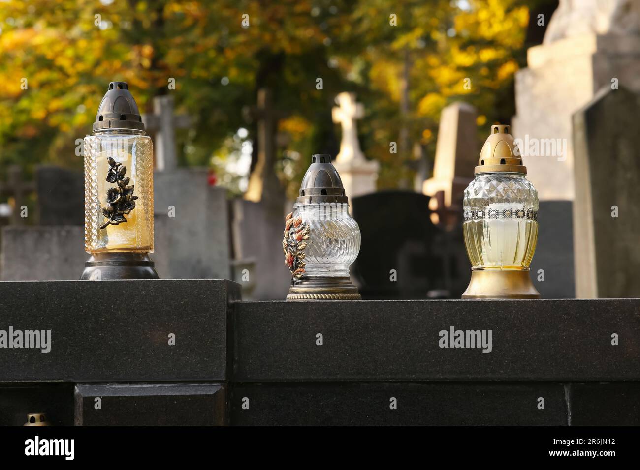 Different grave lanterns on granite tombstone outdoors. Funeral ceremony Stock Photo - Alamy