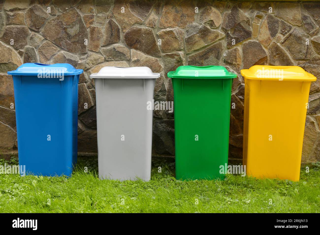 Many colorful recycling bins near stone fence outdoors Stock Photo - Alamy