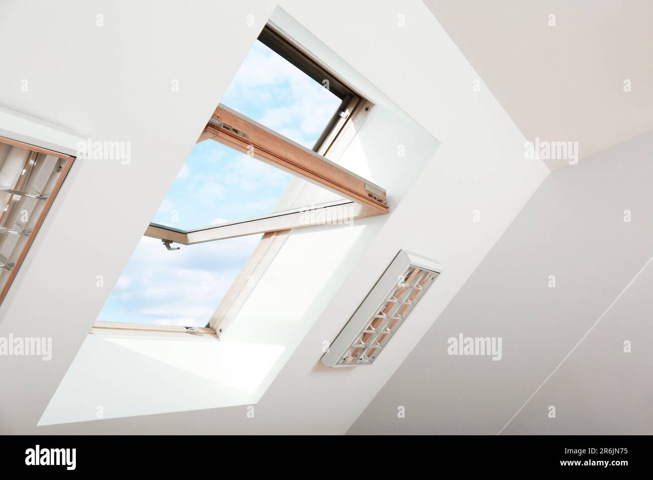 Open skylight roof window on slanted ceiling in attic room, low angle ...